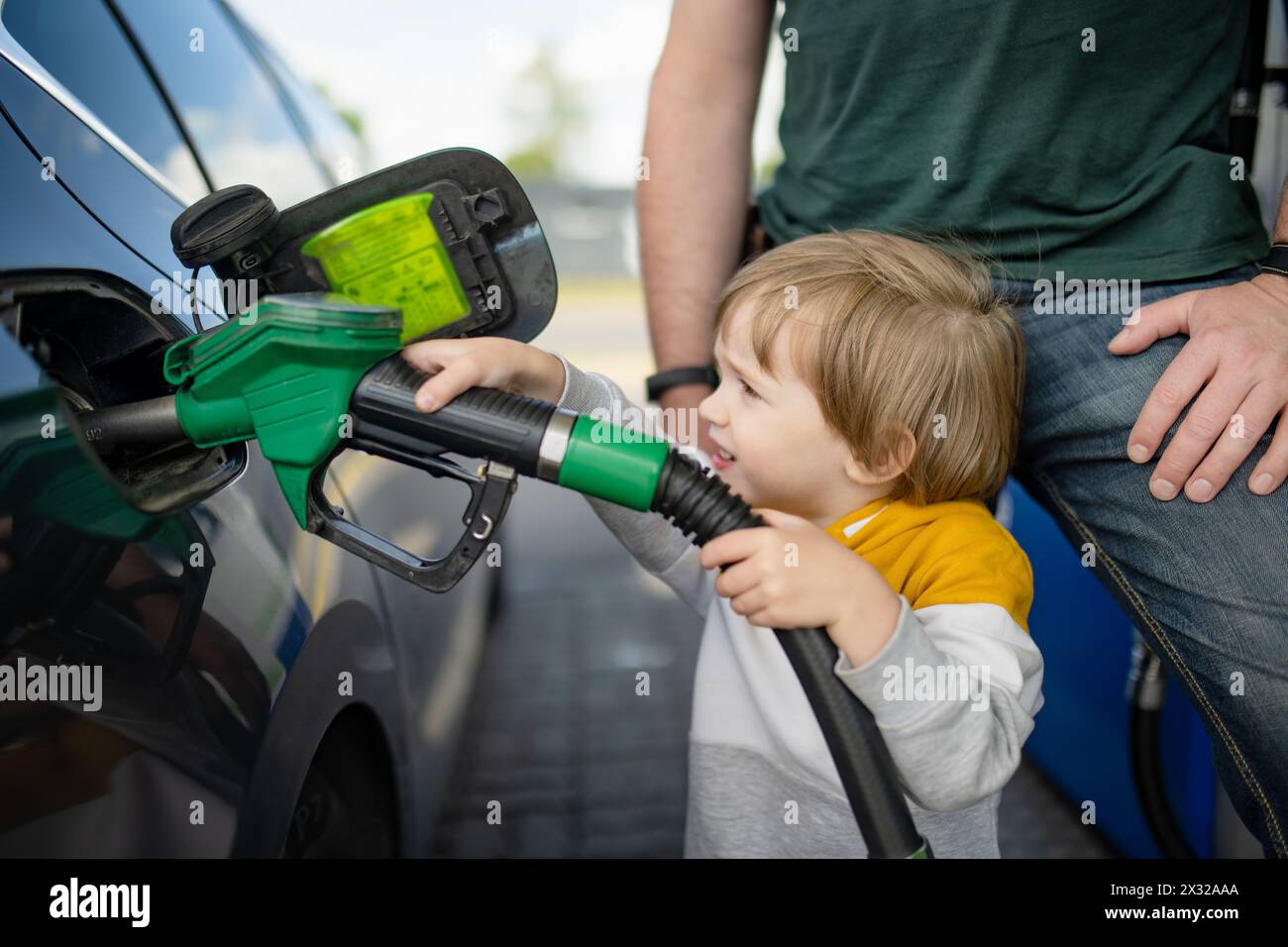 Cute little blond boy holding pump nozzle. Small funny kid helping ...
