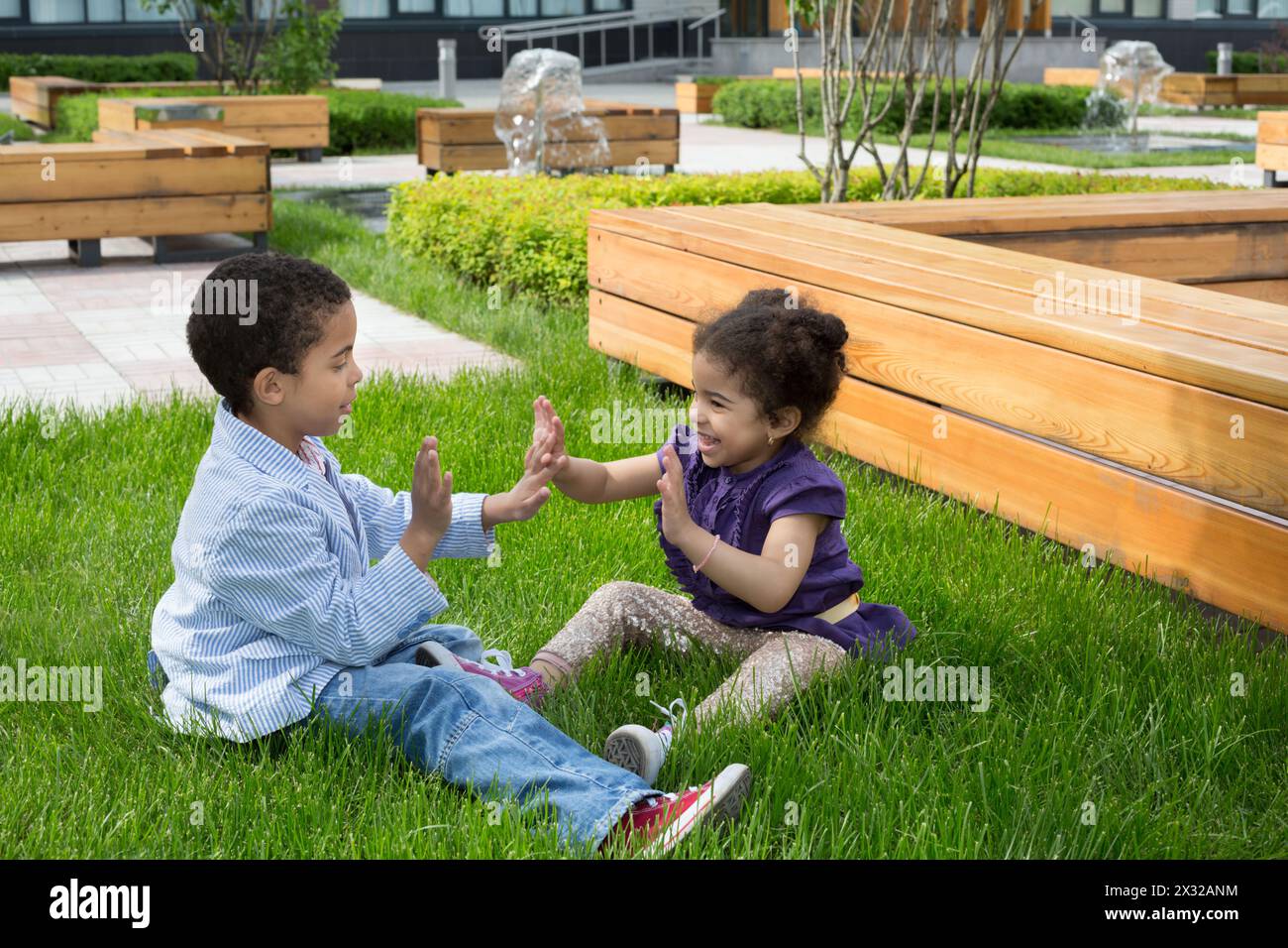 Brother and sister sitting on the grass and clap each other hands Stock Photo - Alamy