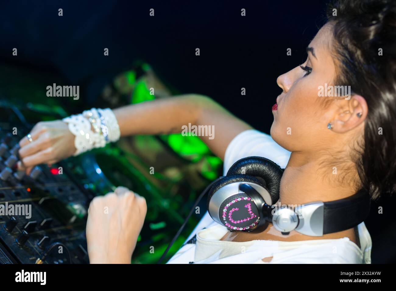Girl DJ with headphones around neck standing behind the machine in ...