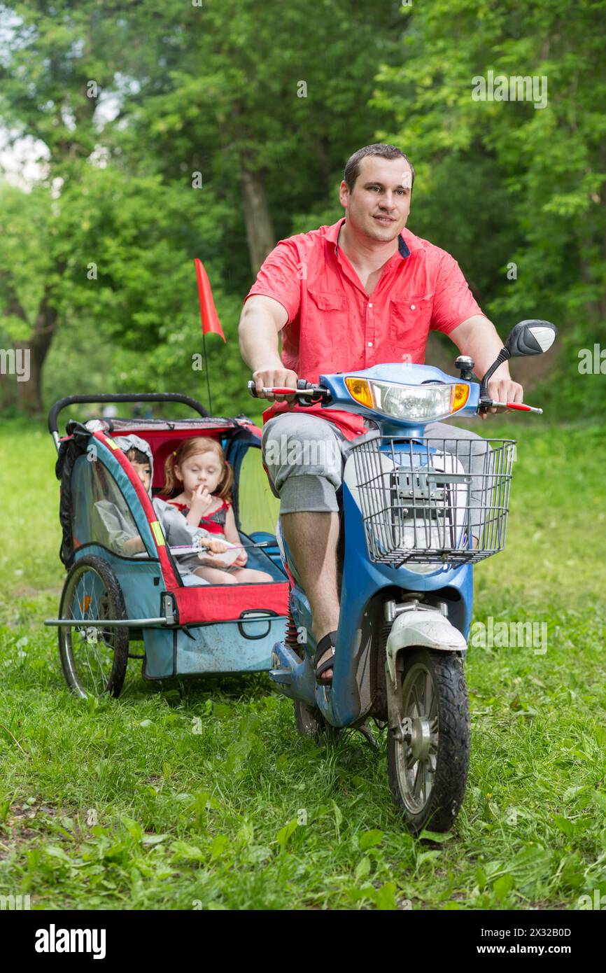 Father on a unreal design scooter with two children in cart ride on ...