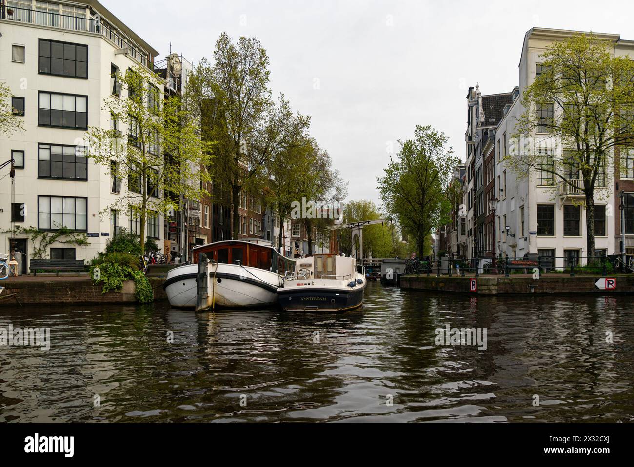 Two boats moored in side canal with drawbridge viewed from canal cruise ...
