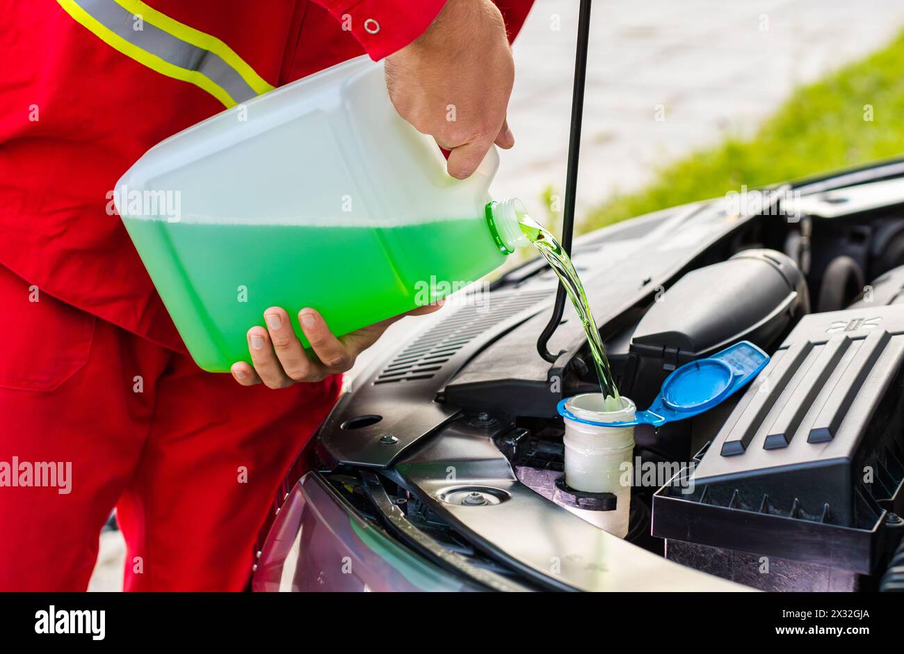 Close-up service worker man driver pouring green non freezing ...