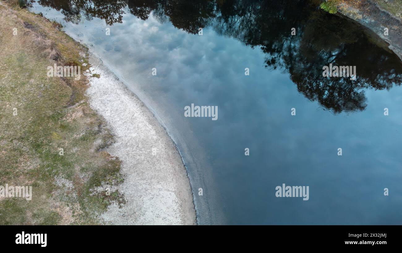 Look down on river blue water surface with clouds reflection, grass and ...