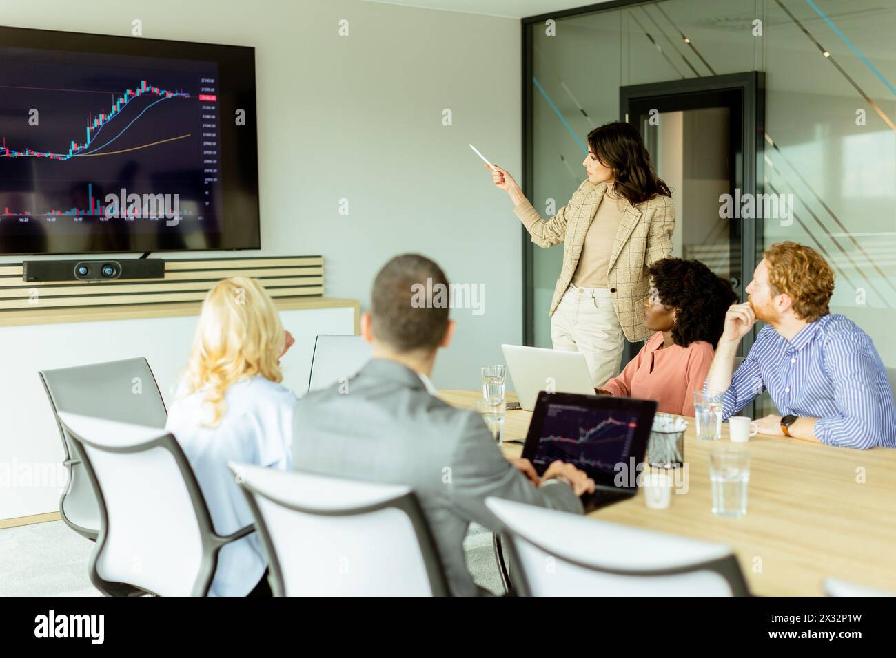 Businesswoman points at growth trends on a screen during a financial ...