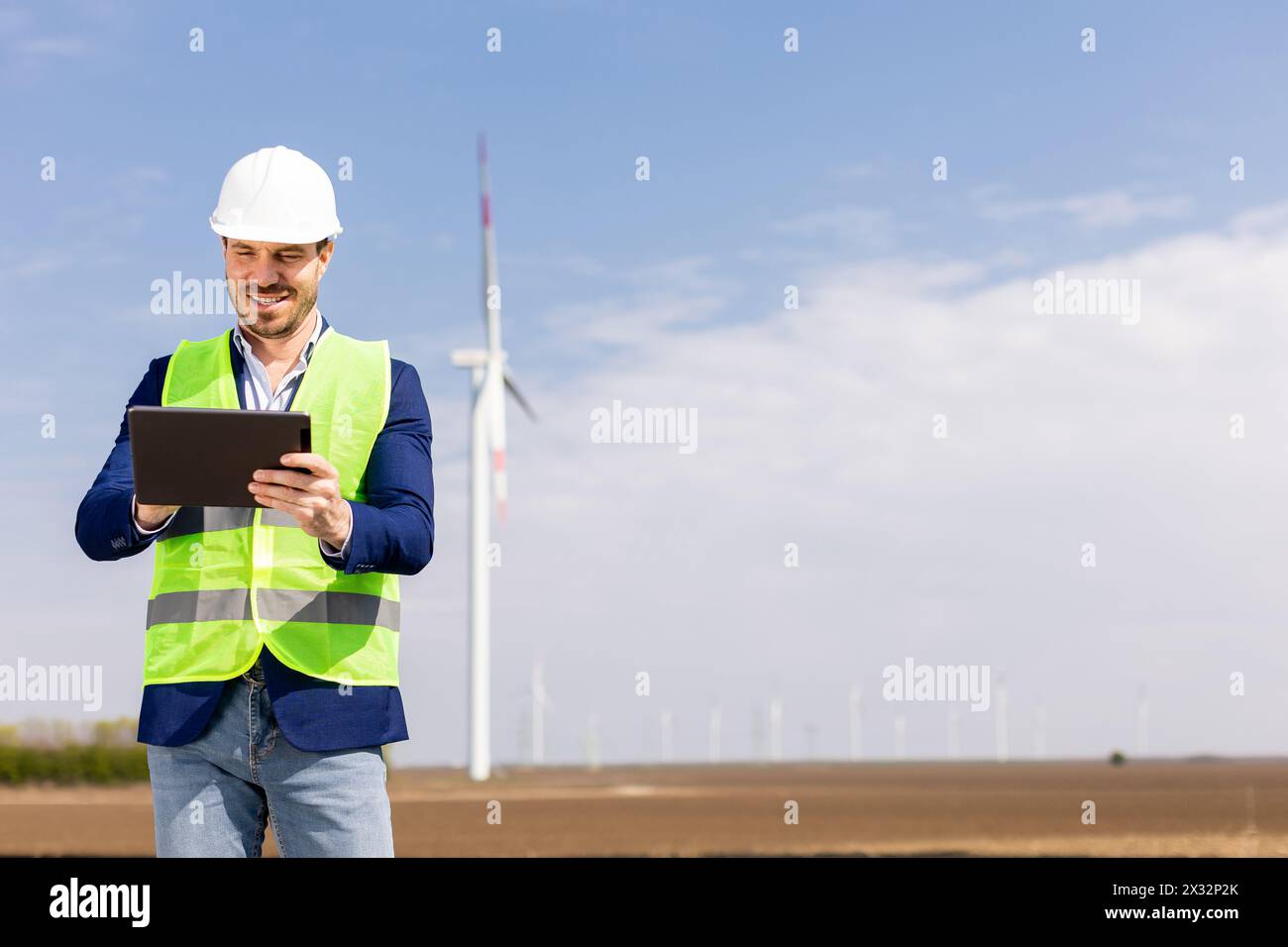 A cheerful engineer in safety gear reviews data on a tablet before ...