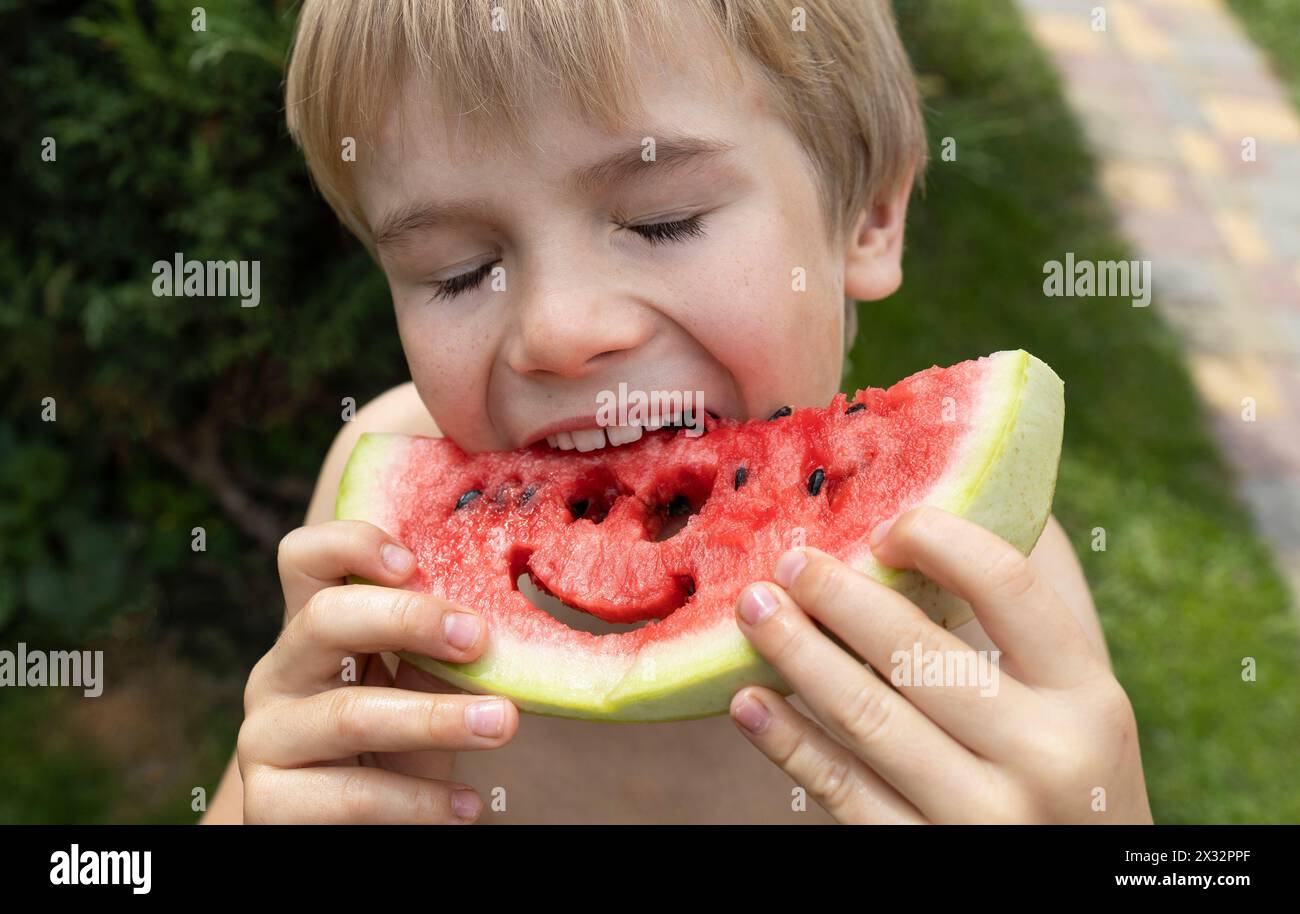 child enjoys the taste of watermelon, biting the juicy red pulp Stock ...