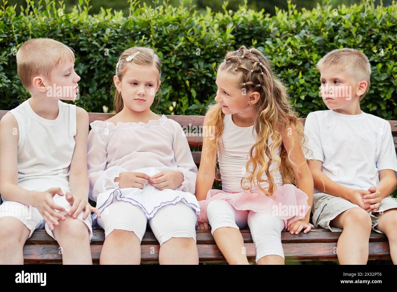 Four children sit on bench in summer park and talk abot something Stock ...