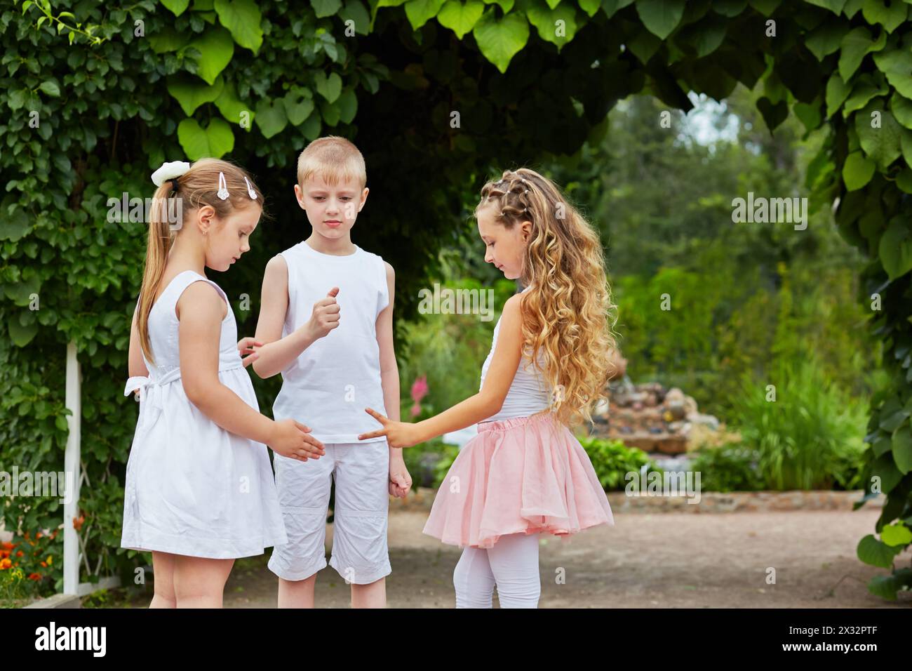 Two little girls and boy play in rock-paper-scissors standing on ...