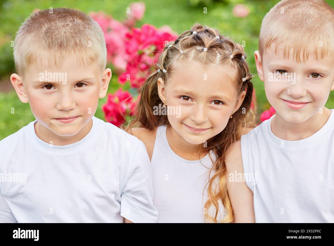 Closeup portrait of three children with flowers at background Stock ...
