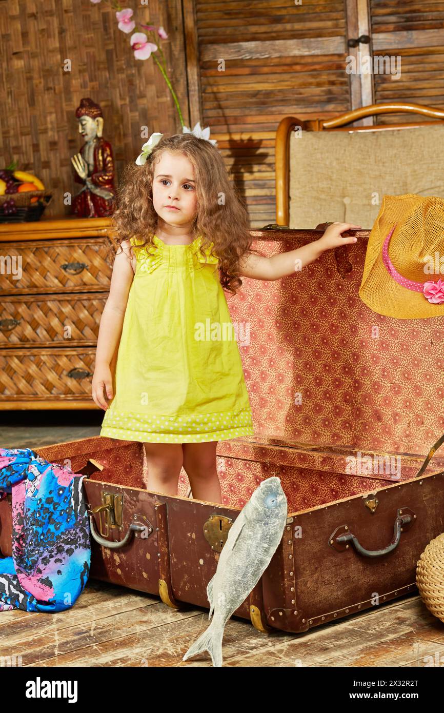 Little girl in yellow dress stand in opened old big ragged fiber ...