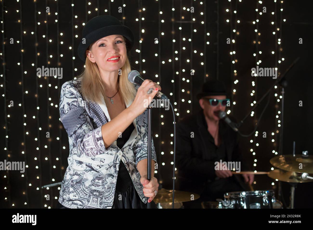 Lead singer stands at microphone in studio with drum set Stock Photo ...