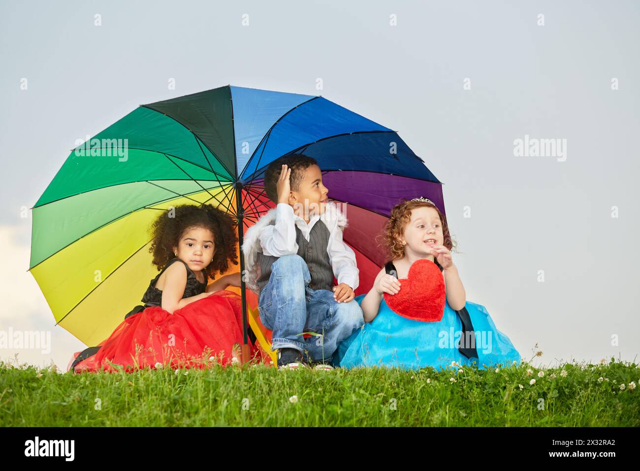 Little boy and two little girls hide from rain sitting under big ...