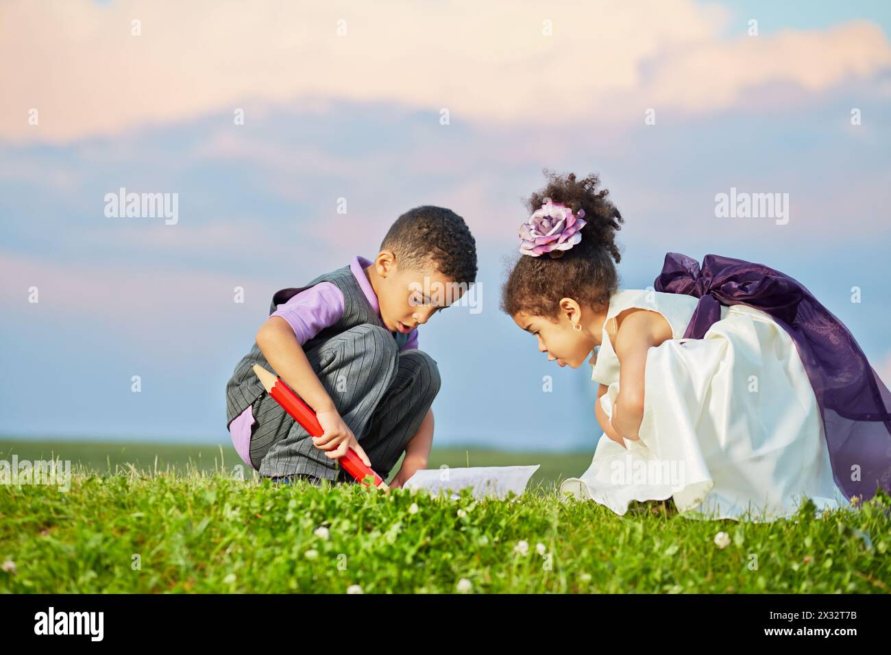 Little boy in grey suit and little girl in light gown with violet ...