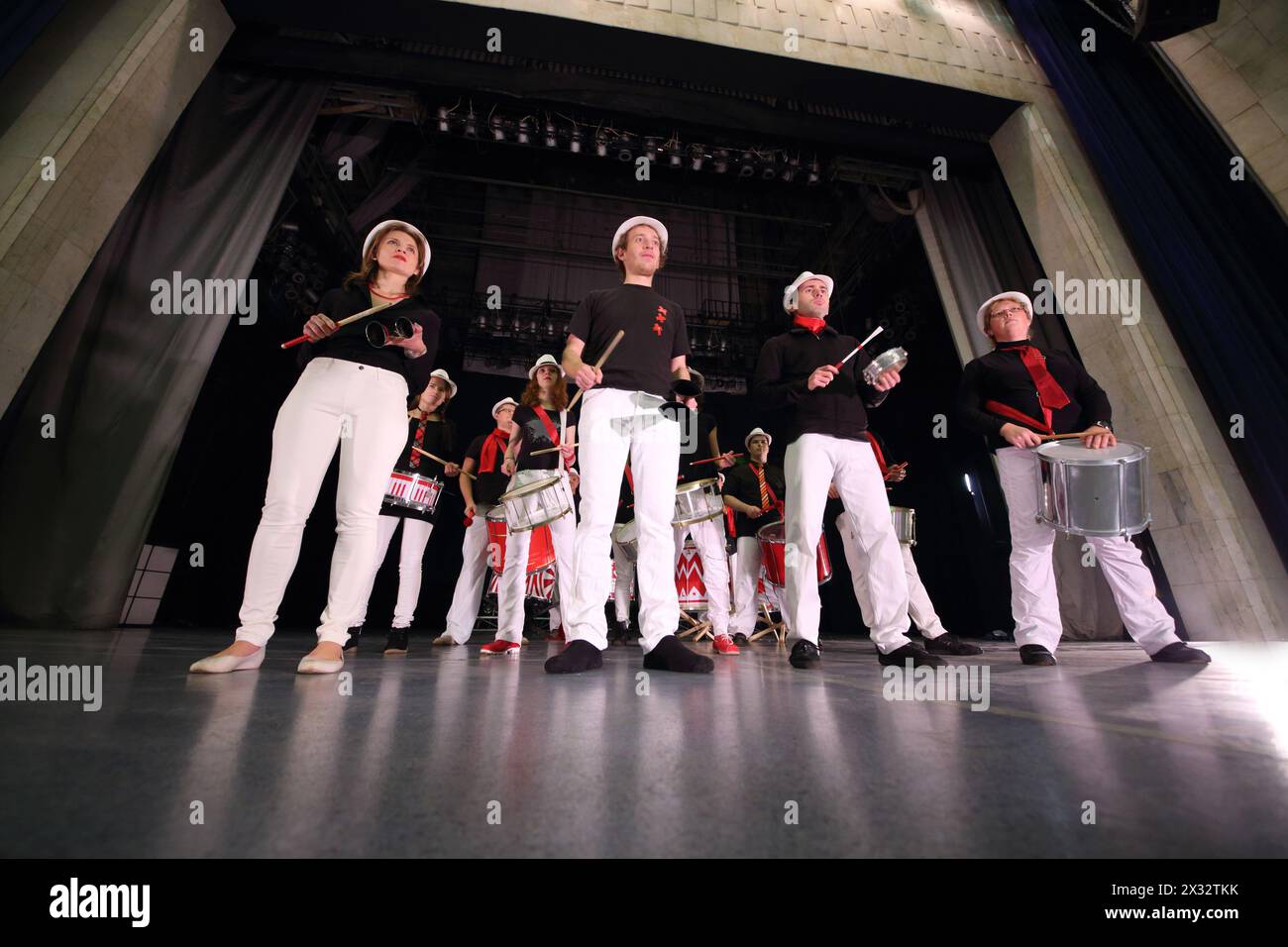A group of eleven people in the same costumes rehearsing with the drums ...