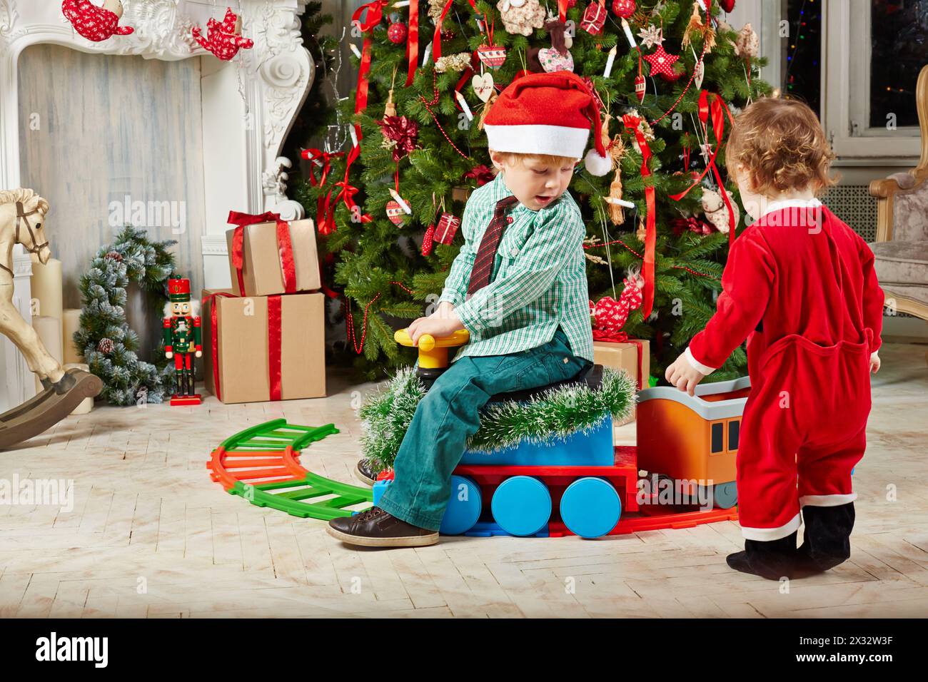 Little boy in Santa cap rides toy plastic steam engine at room ...