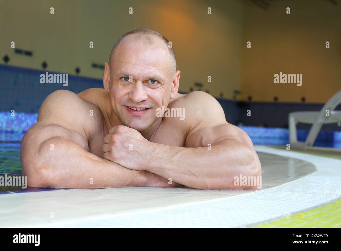 Happy bodybuilder relies on curb of swimming pool of gym hall Stock ...