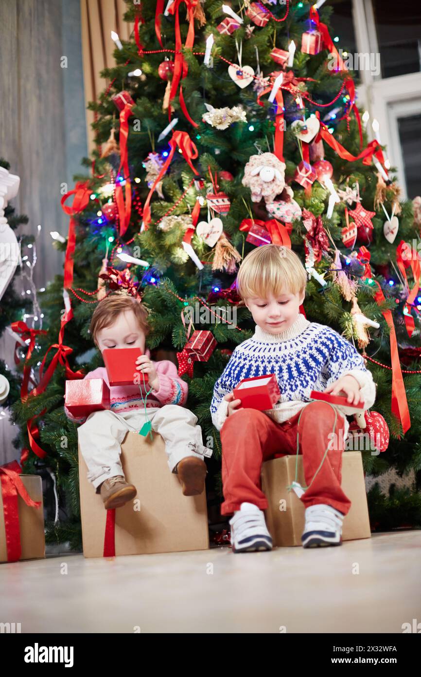 Little boy and little girl sit on big cardboard gift boxes under ...