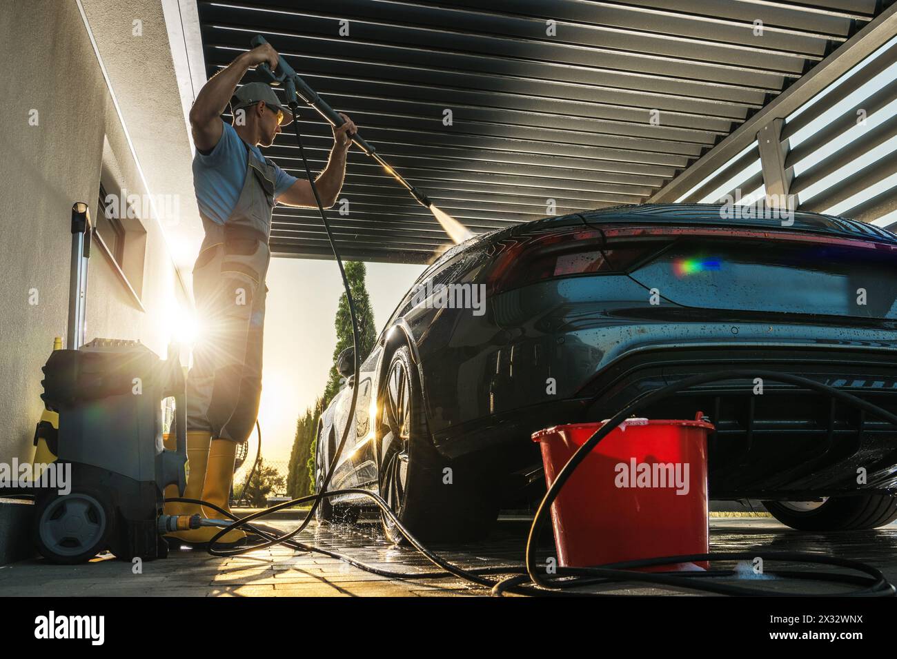 Caucasian Man Pressure Washing His Modern Car Inside a Carport. Sunny ...