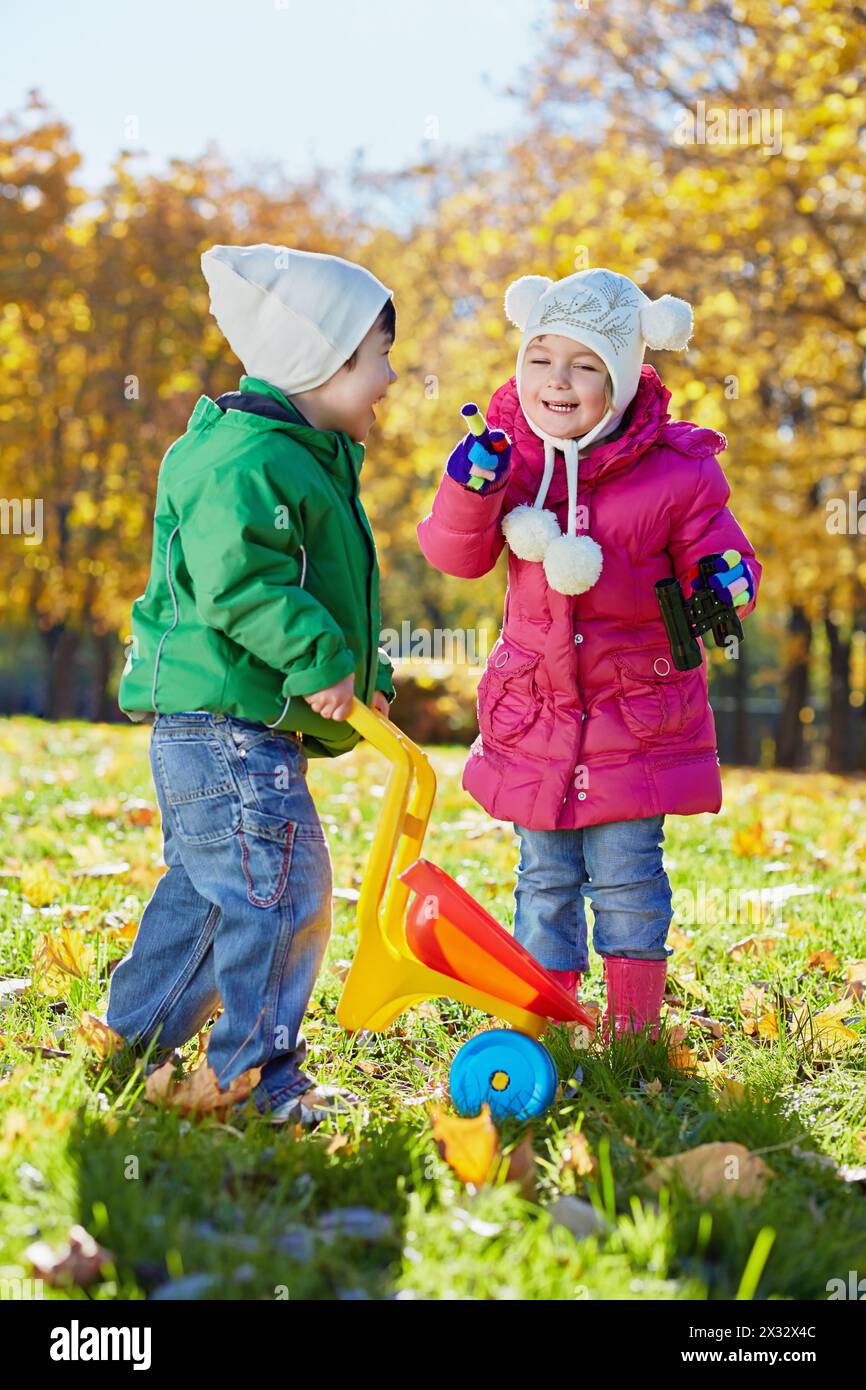 Little boy with plastic wheelbarrow and little girl with binocular ...