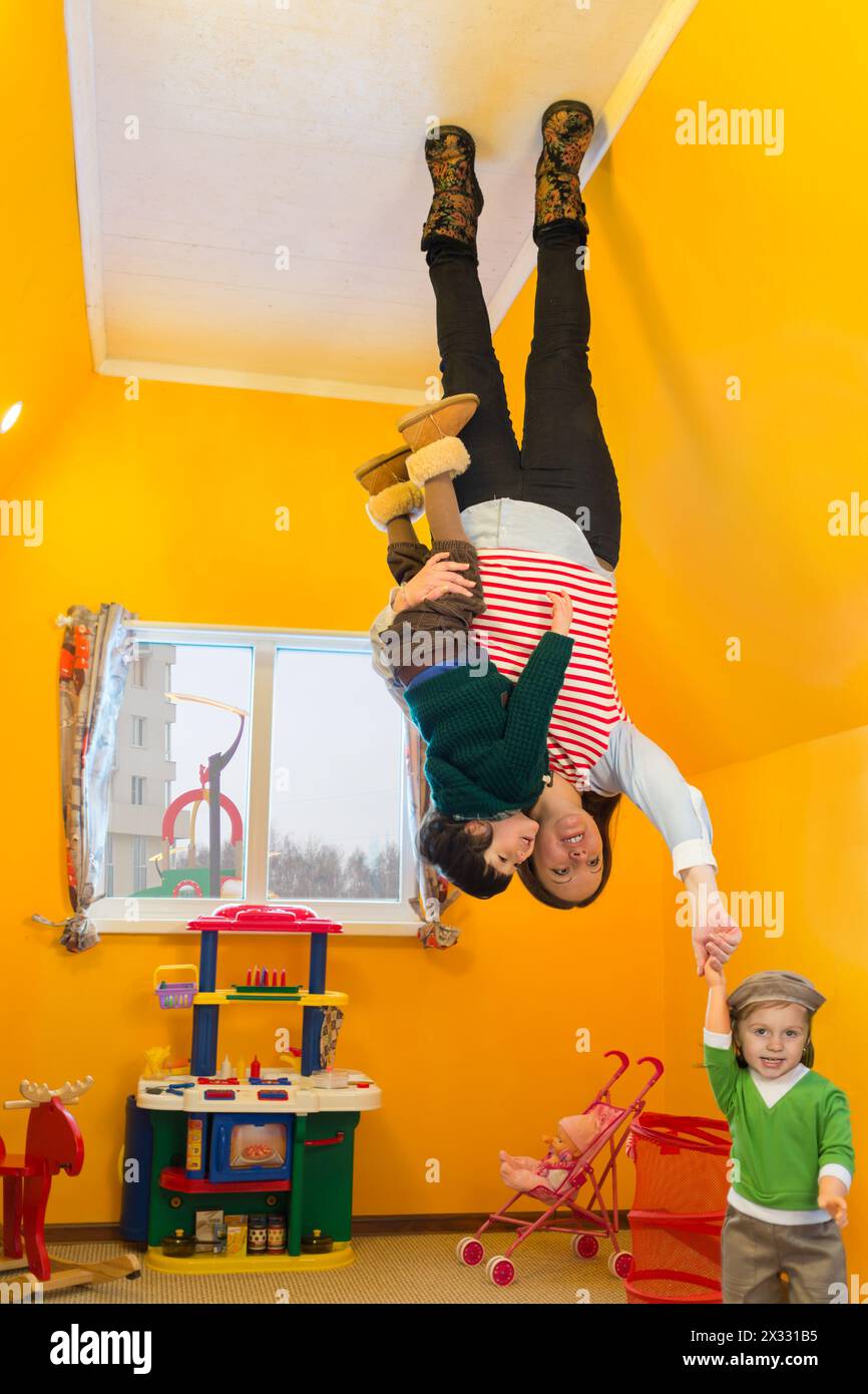 Mother and daughter standing on the ceiling of childrens room and ...
