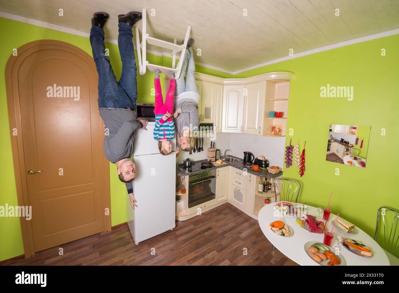Family of three upside down in the kitchen with table and fridge Stock ...