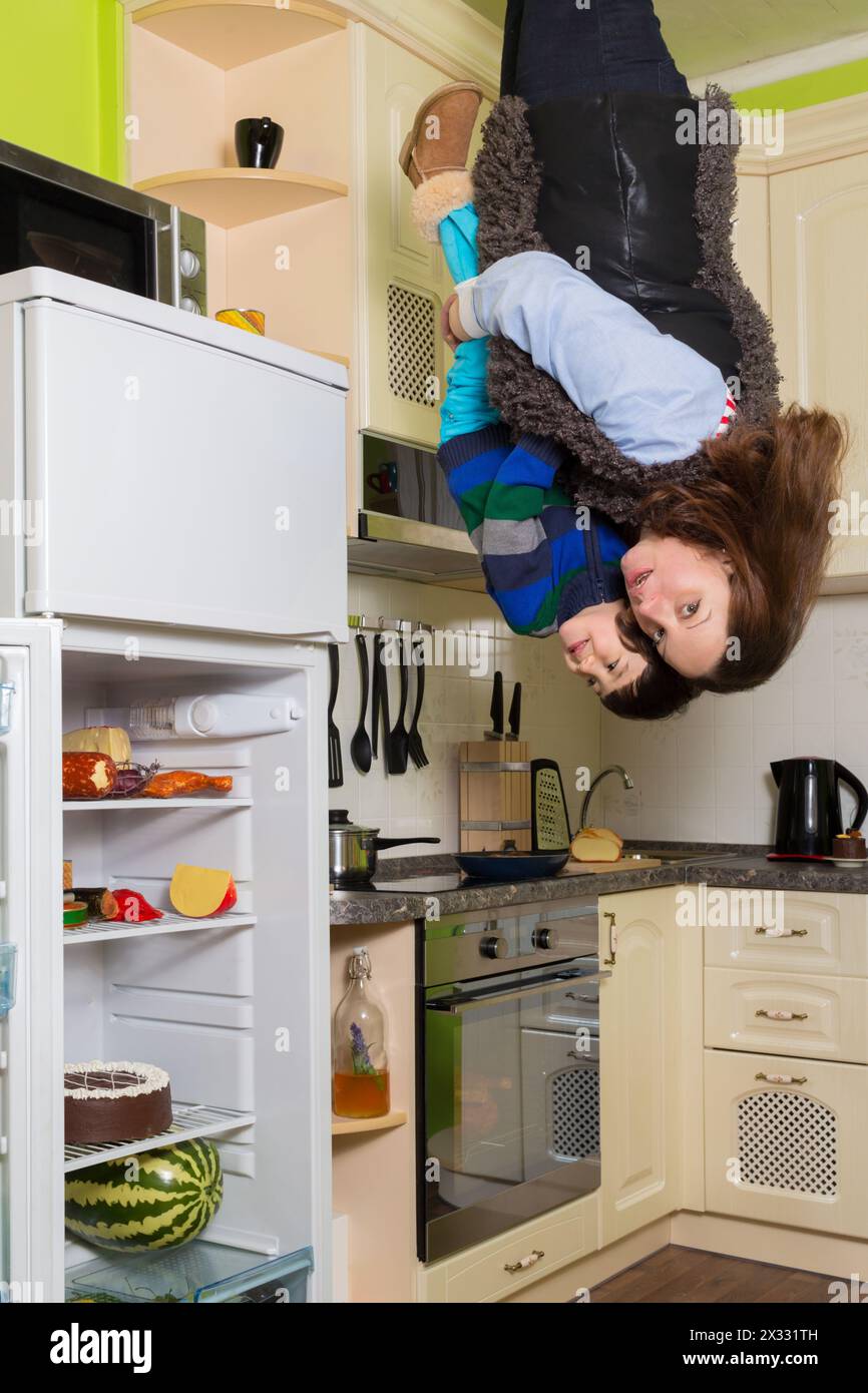Mother with son stand upside down in the kitchen with fridge Stock ...