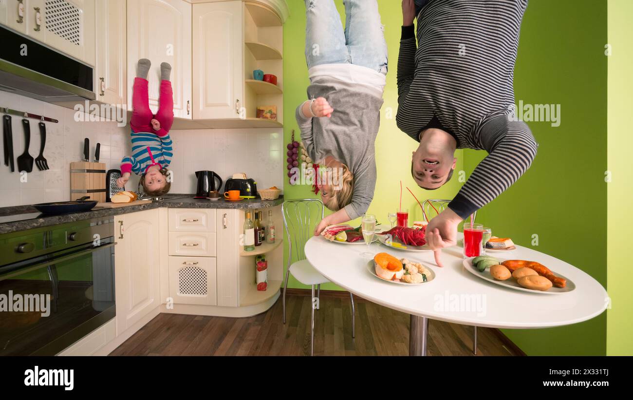 Family of three upside down in the kitchen with table and dishes Stock ...