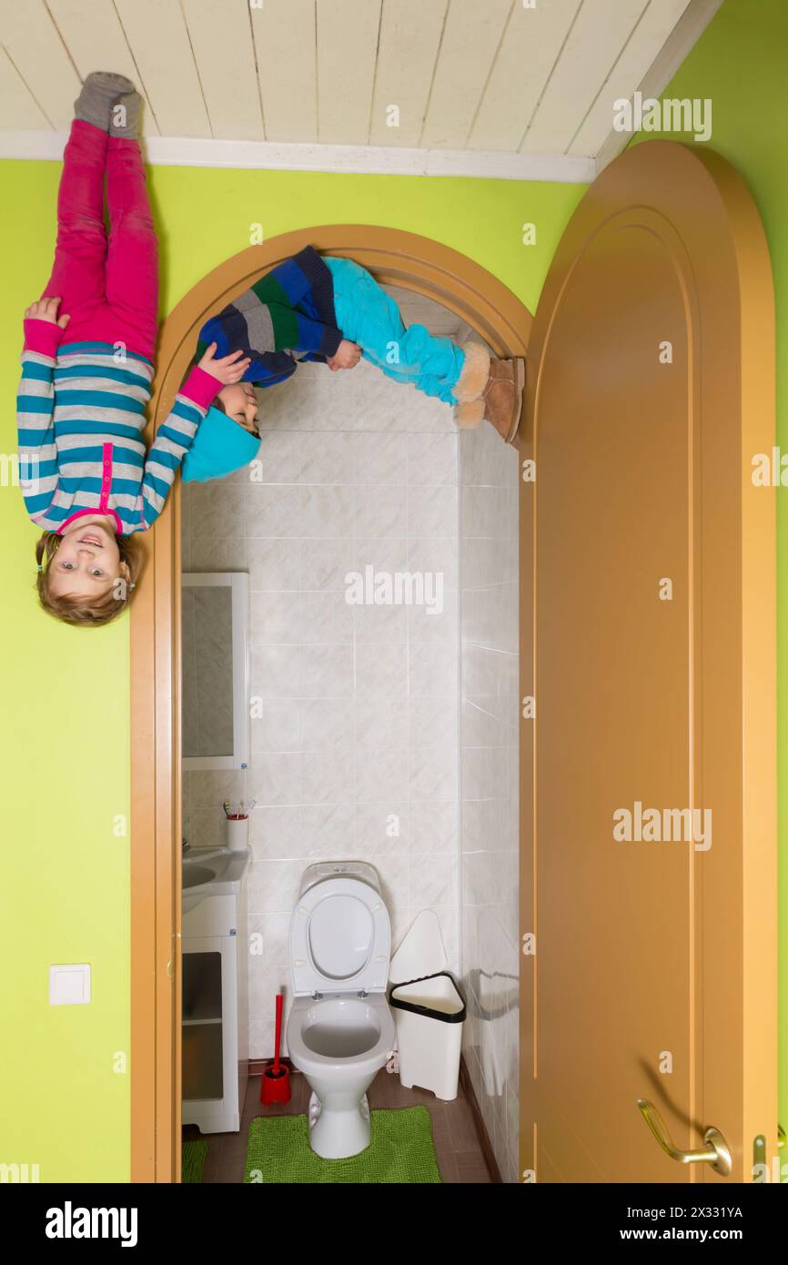 Two children upside down on the ceiling near toilet at inverted house ...