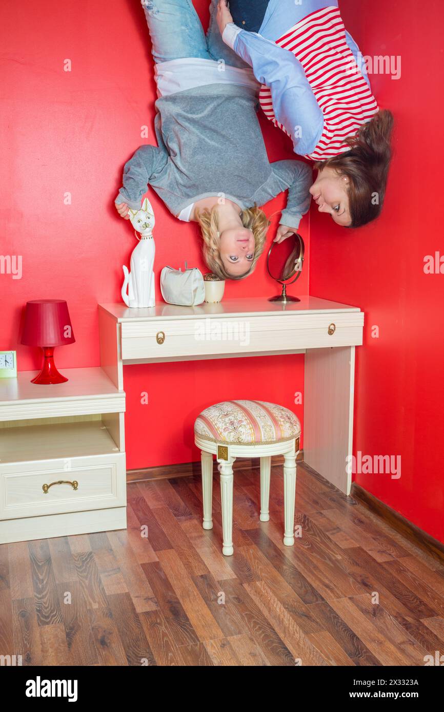 Two girls upside down in the bedroom above the dressing table Stock ...