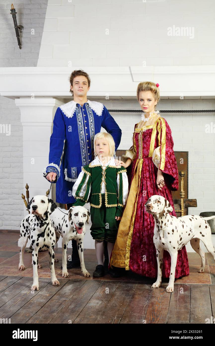 Father, mother and son in bright medieval costume pose near fireplace ...