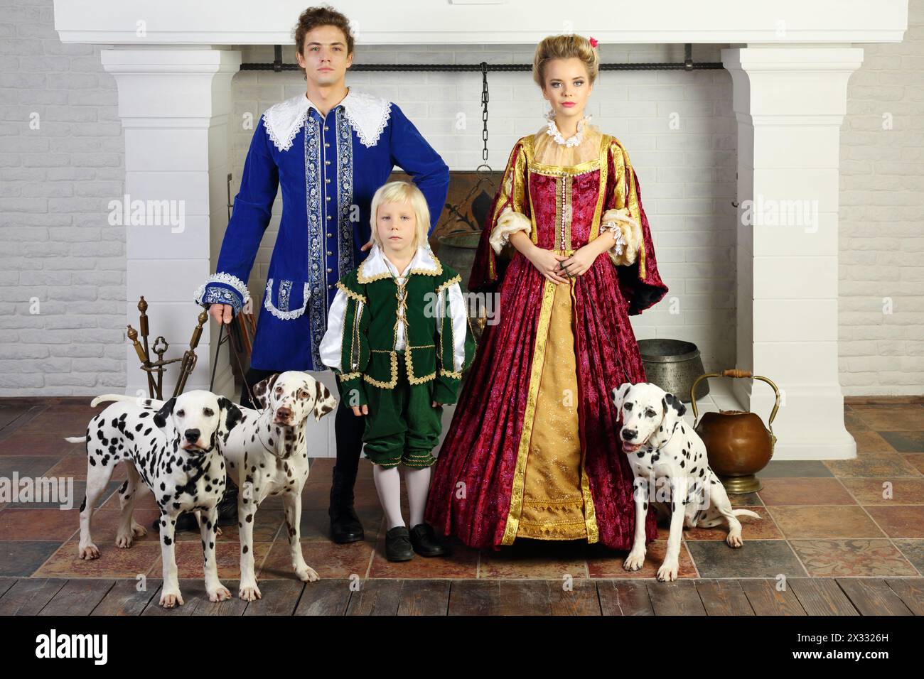 Father, mother and son in medieval costumes stand near fireplace with ...