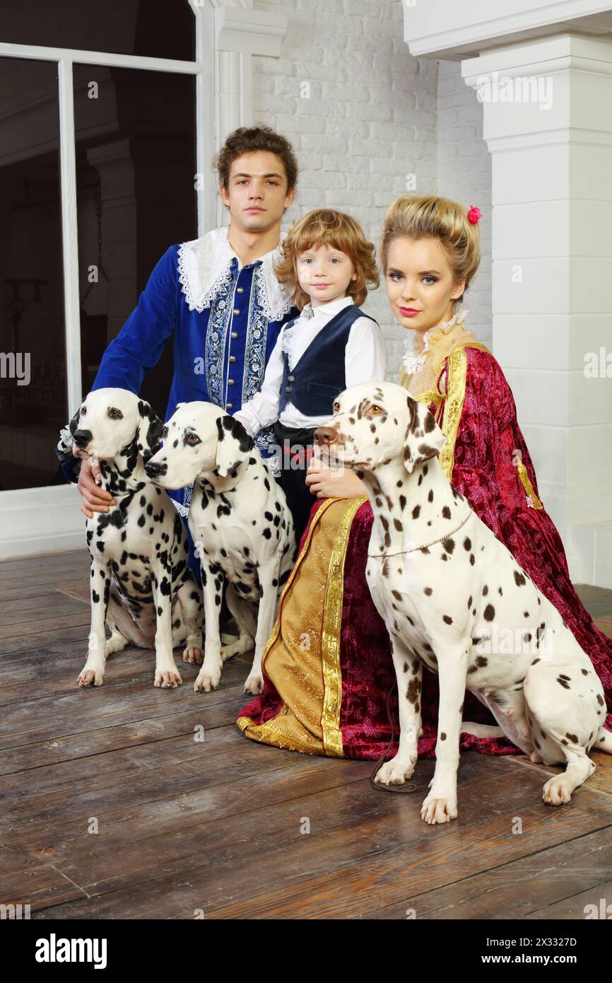 Young father, mother and little son in medieval costumes near window ...