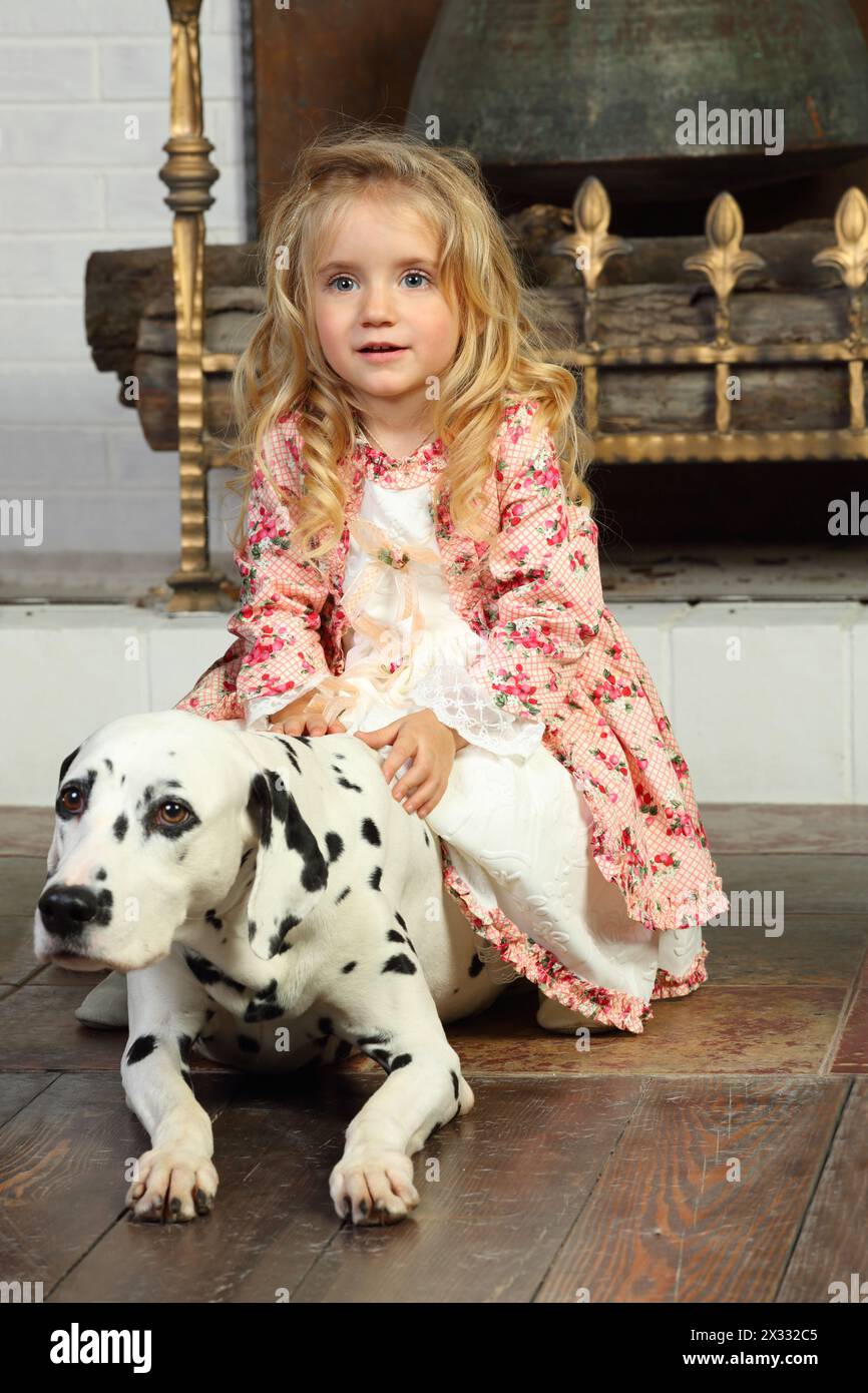 Happy pretty little girl in medieval costume sits with dalmatian near ...