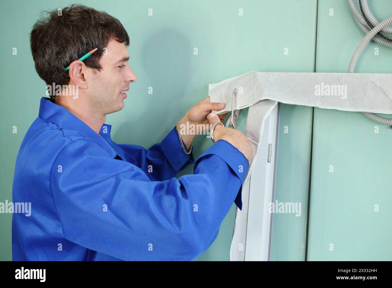 A man prepares a new window frame for installation in a window aperture ...