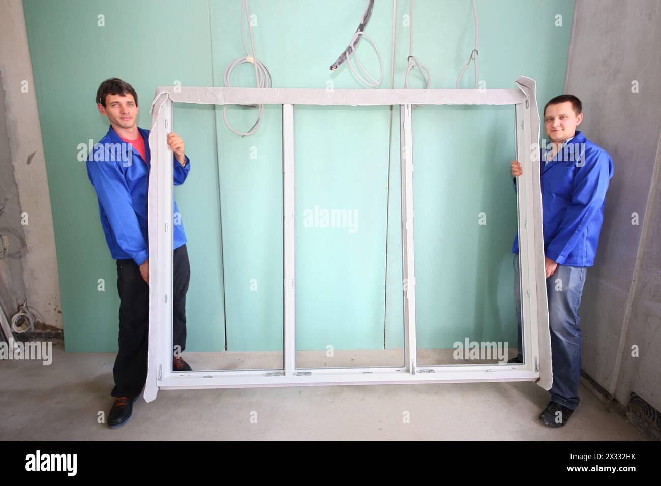 Two men holding new window frame in a room under renovation Stock Photo ...