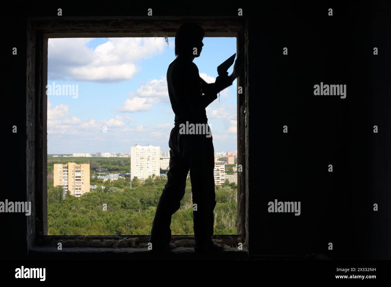 Silhouette of a worker with a spatula in his hand in a window aperture ...