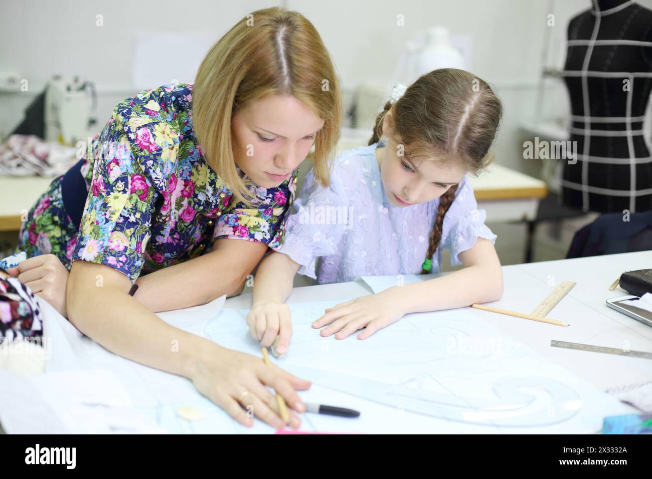 Female tailor teaches student girl how to draw patterns for clothes ...