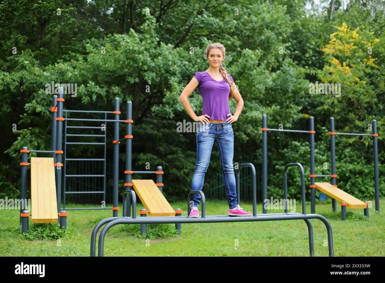 Beautiful girl standing on the parallel bars on the outdoor sports ...