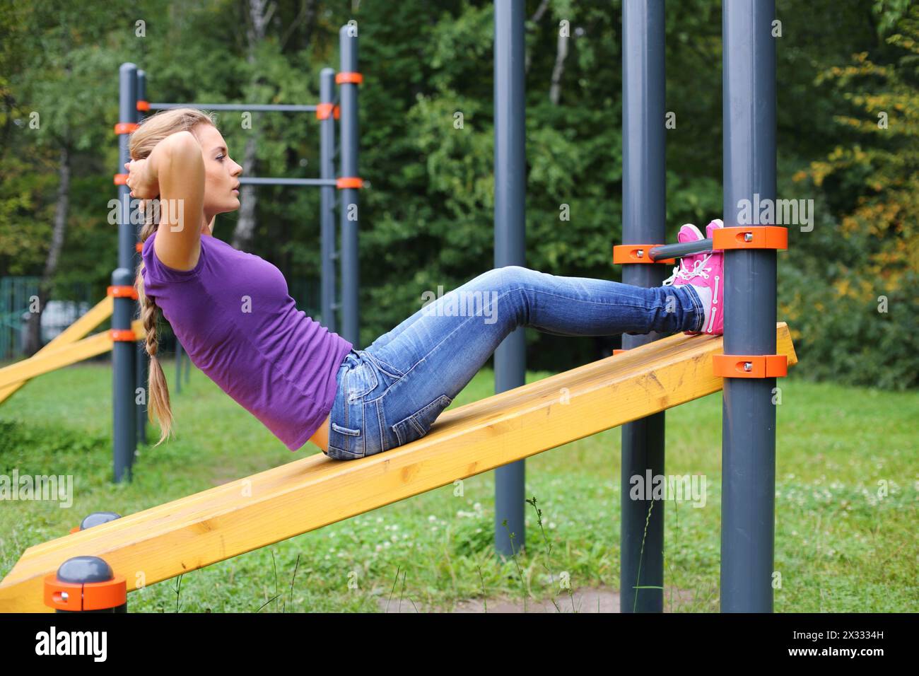 A young girl doing abdominal crunches on the outdoor sports ground ...