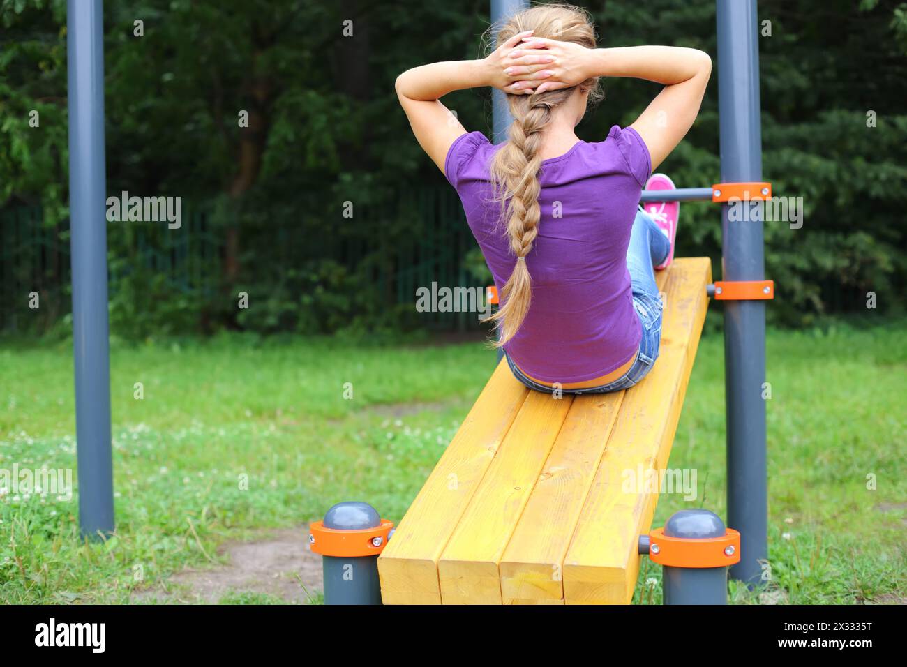 A young girl doing abdominal crunches on the outdoor sports ground ...