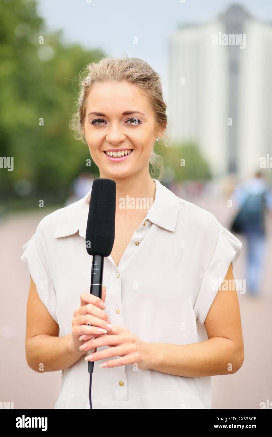 Girl reporter in white blouse and with a microphone on the street Stock ...