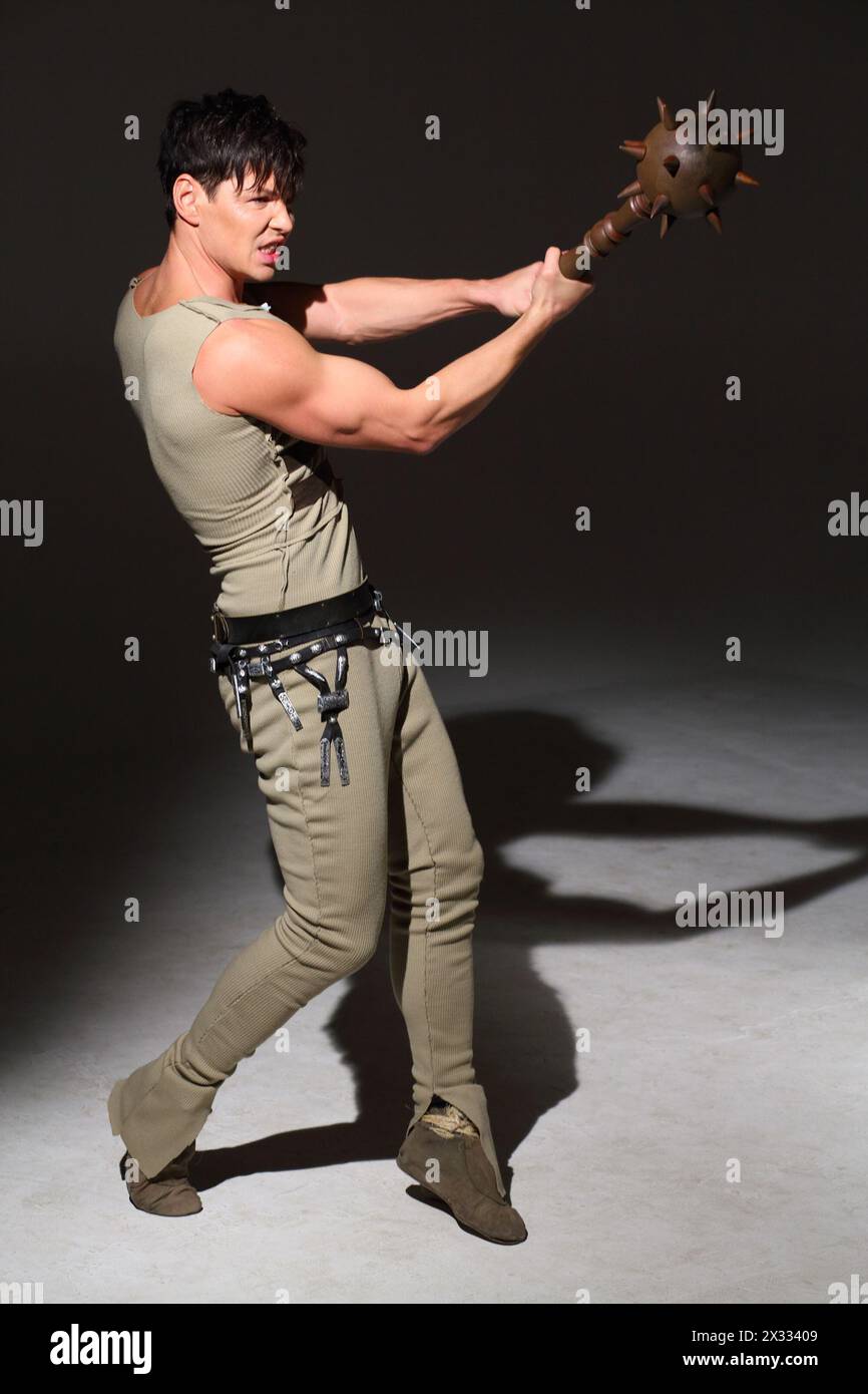 Strong young man in a costume is hit with a mace in a dark studio Stock ...