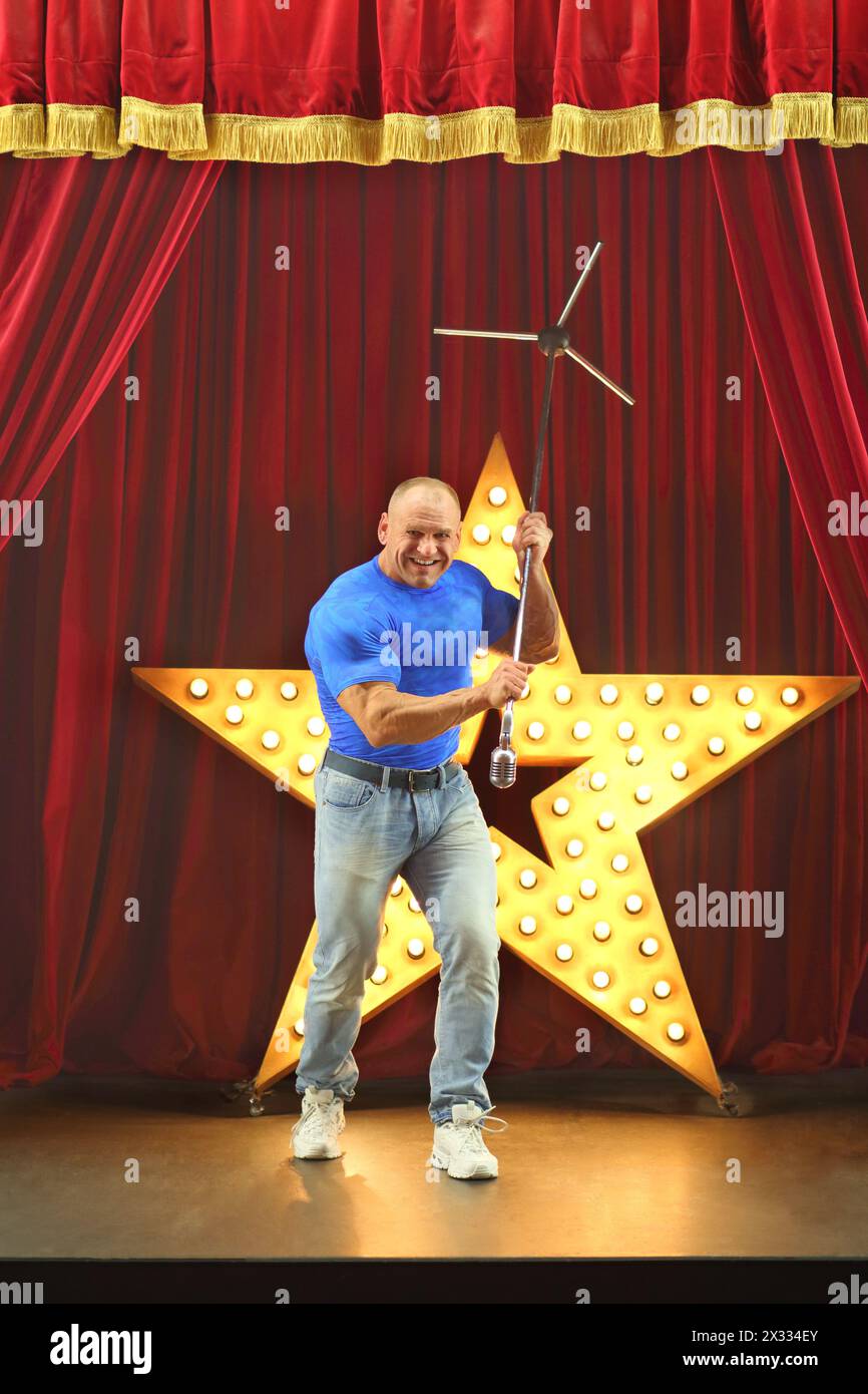 Strong man stands on stage and turned the microphone stand Stock Photo ...