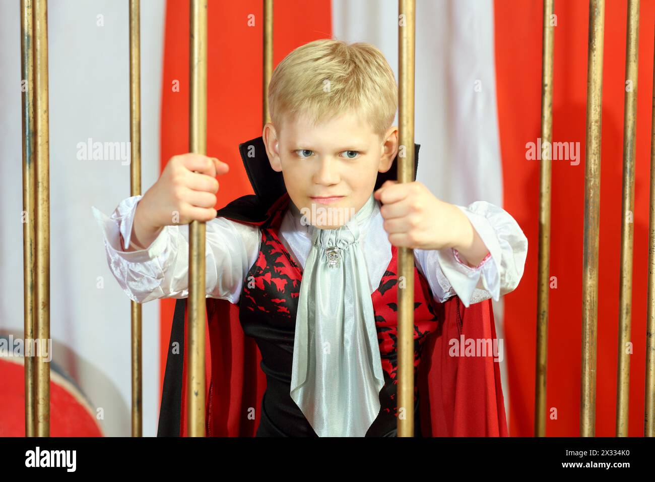 Little boy in black suit and red cloak is pulled out from golden cells ...
