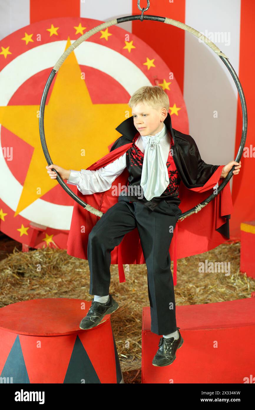 Little boy in black suit and red cloak sitting on air circus ring Stock ...