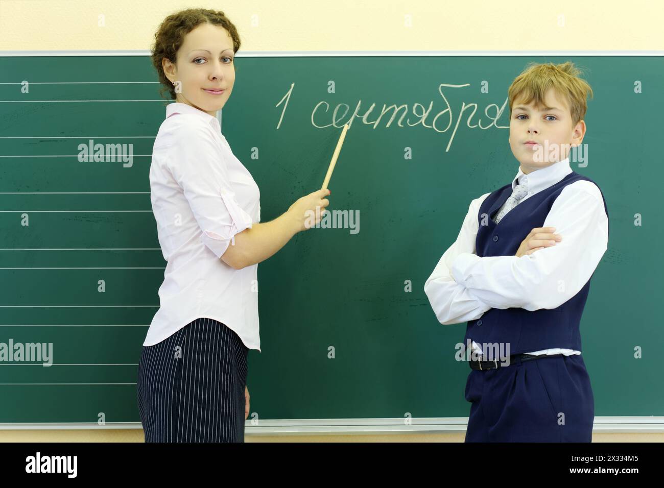 Boy and teacher stand near green chalkboard with inscription September ...