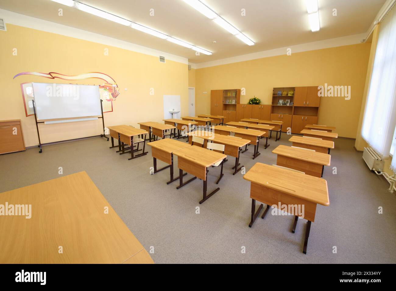 Empty classroom with wooden desks, white chalk board and bookcases in ...