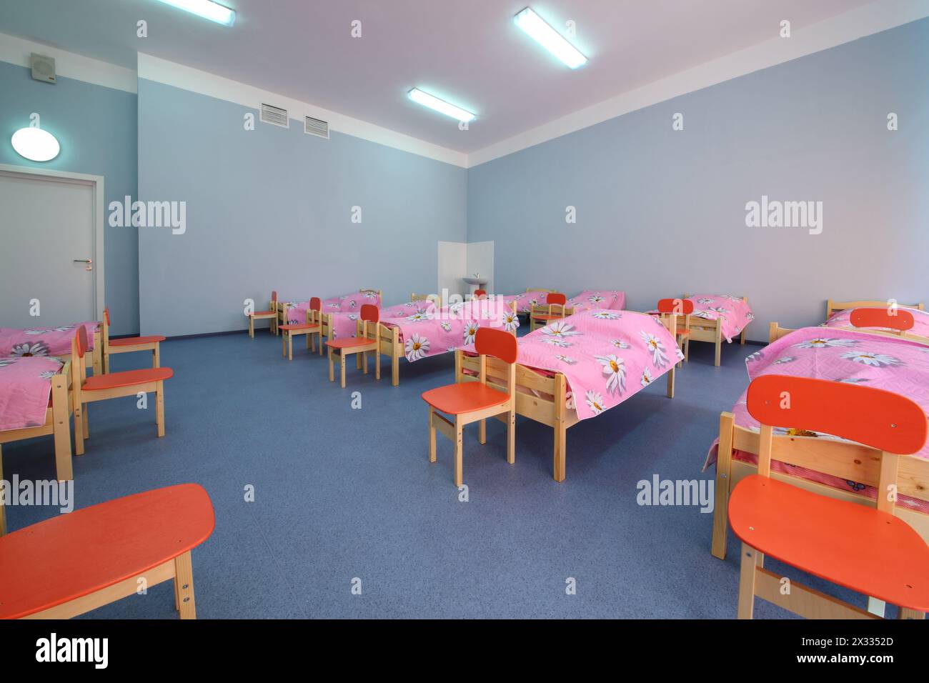 Big empty clean room with wooden beds and chairs and blue walls Stock ...