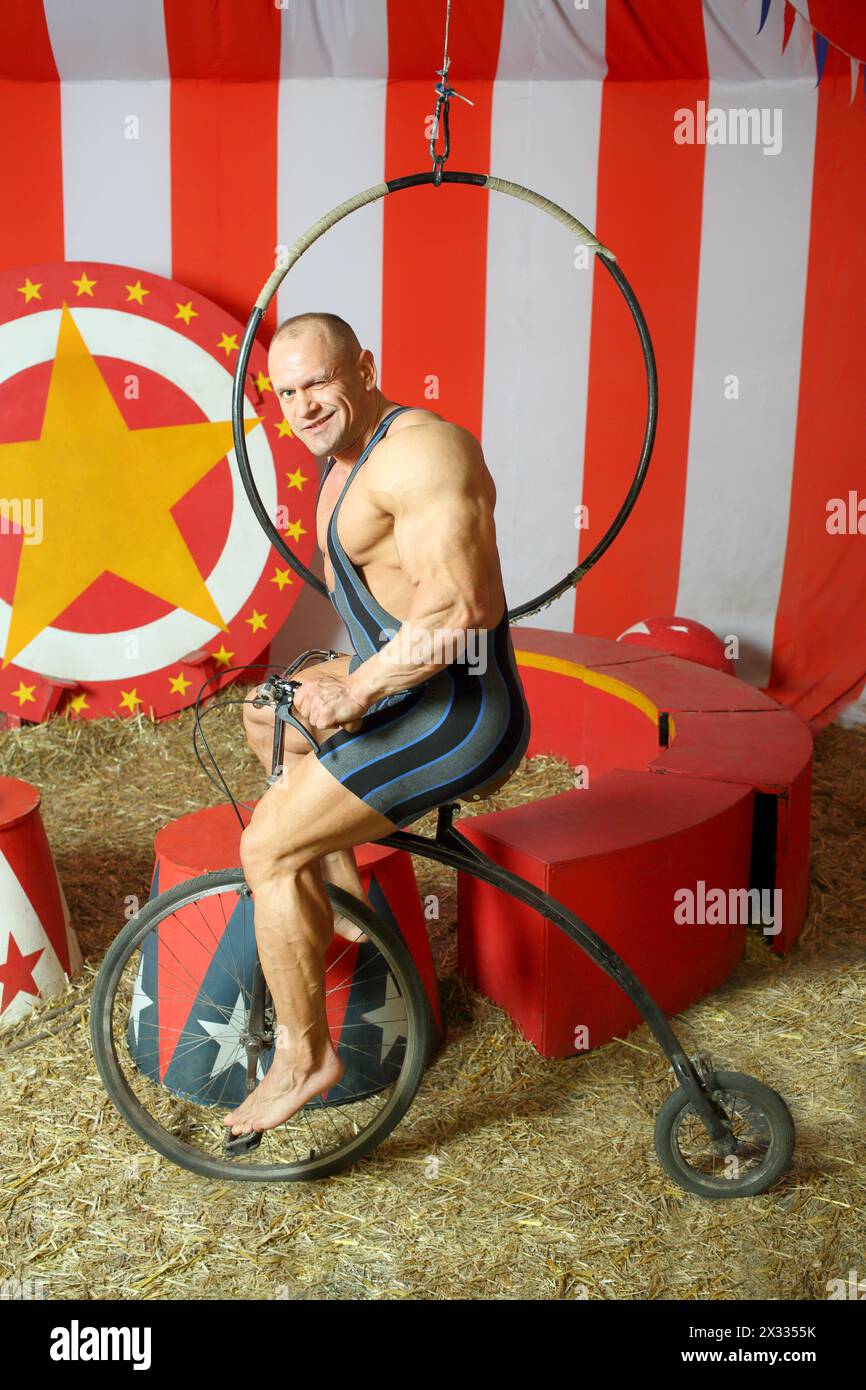 Athlete winking and riding circus retro bike Stock Photo - Alamy