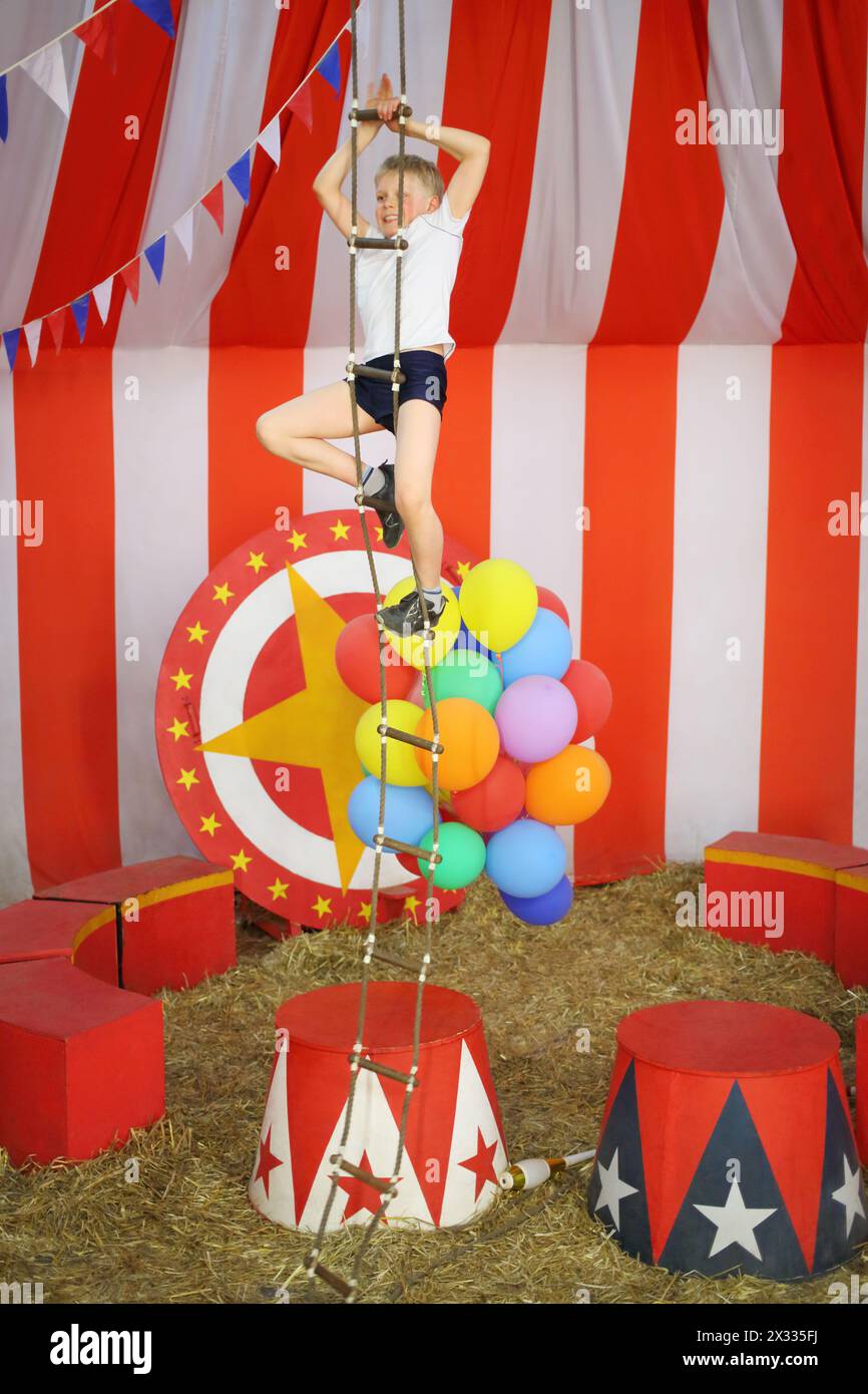 Little boy rises top rope ladder in striped circus tent Stock Photo - Alamy